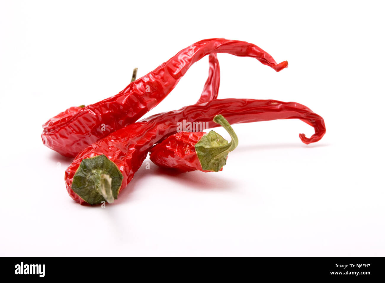 Wrinkled vibrant red chilli's isolated against white background with ...