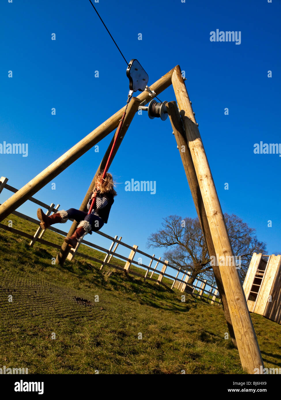 Young girl playing on a rope slide in a children's playground with blue ...