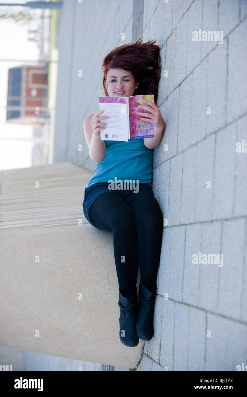 Teenage girl reading book lying down sideways Stock Photo - Alamy