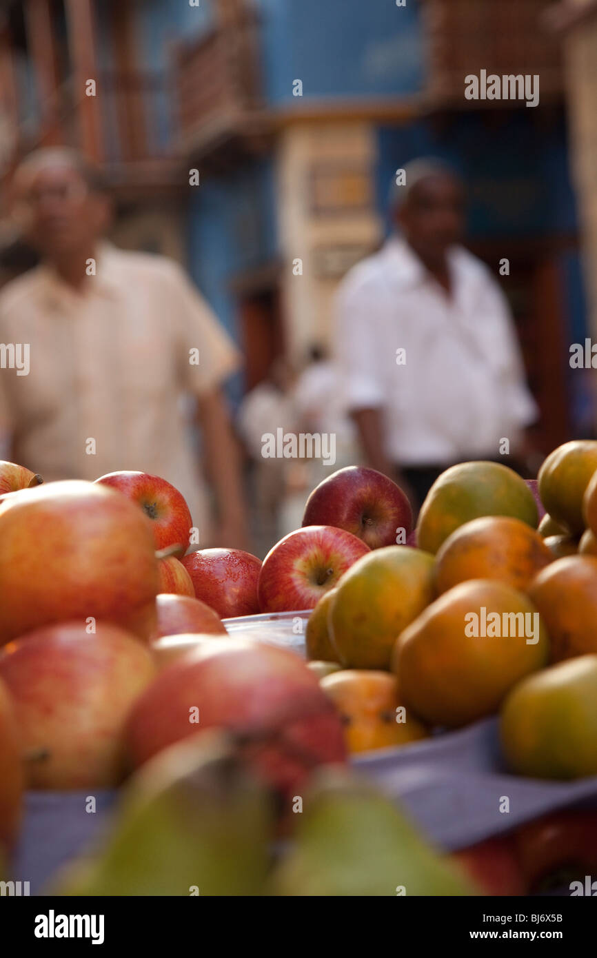 Fruit stall with apples and oranges backlit and blue balconies in the ...