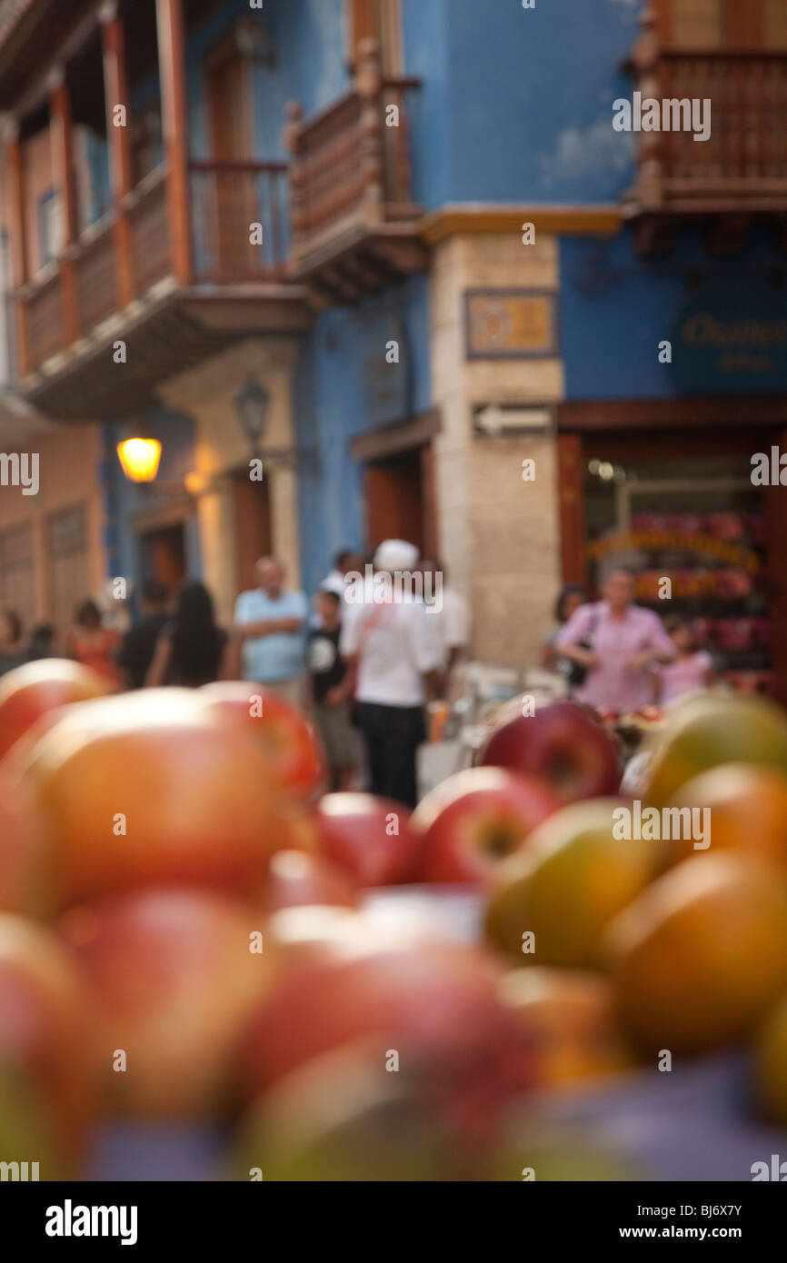 Fruit stall with apples and oranges backlit and blue balconies in the ...