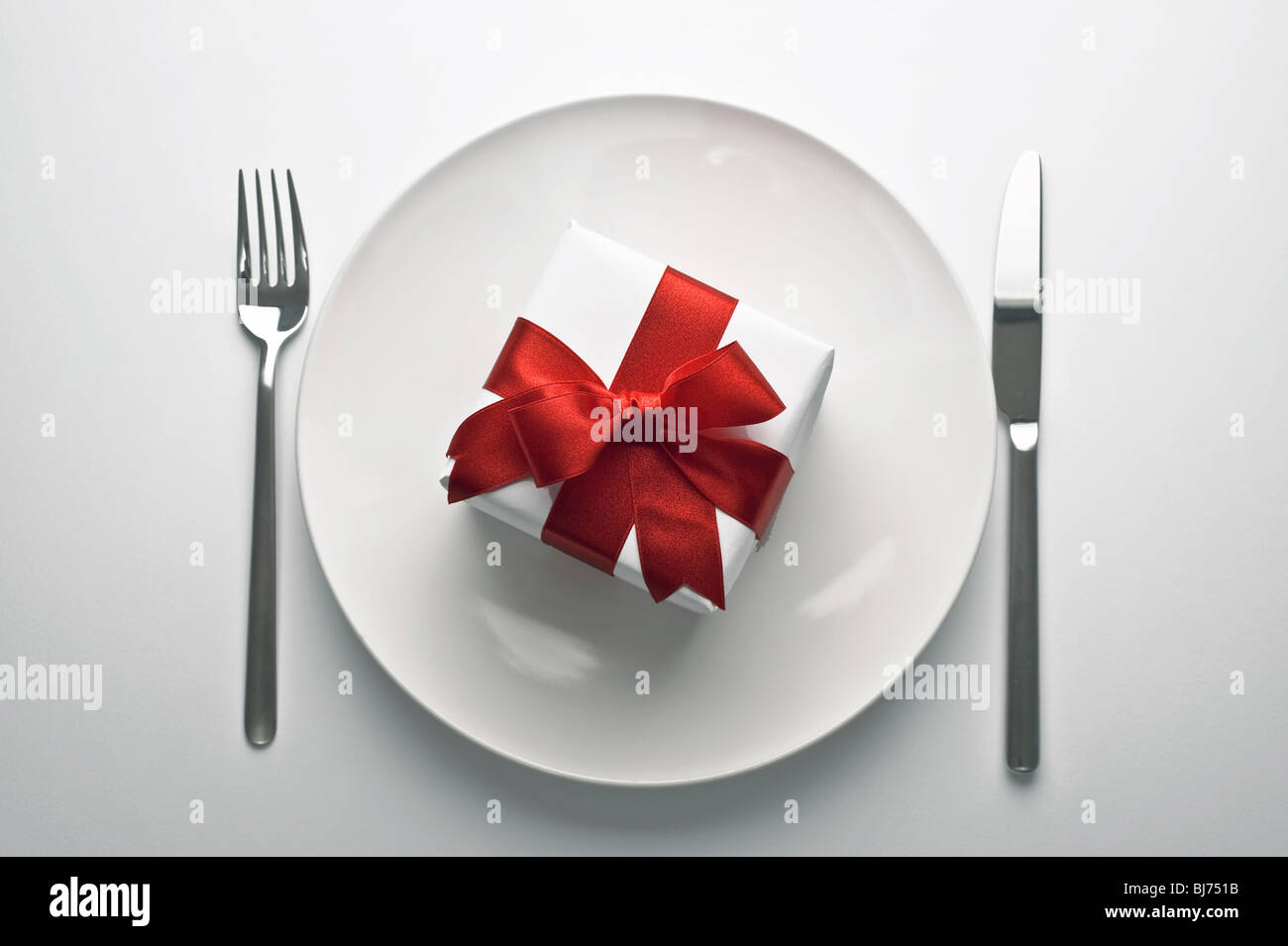 gift with decorative red ribbon on a dinner plate on white background ...