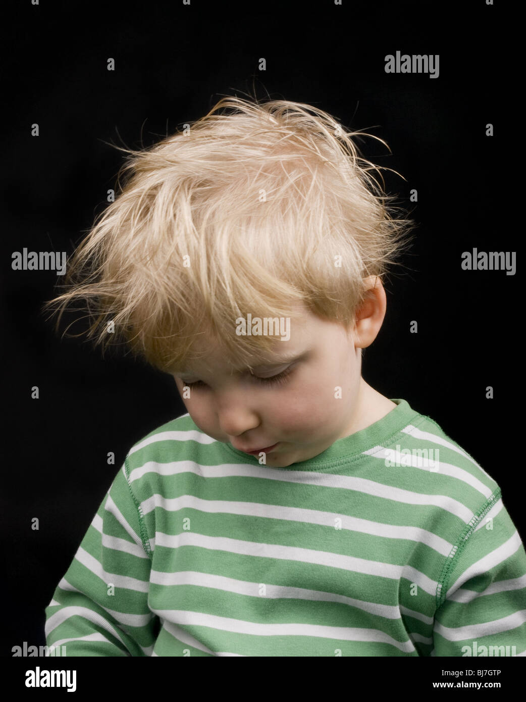 Very sad little boy on black background. Boy have blond hair and a bit ...