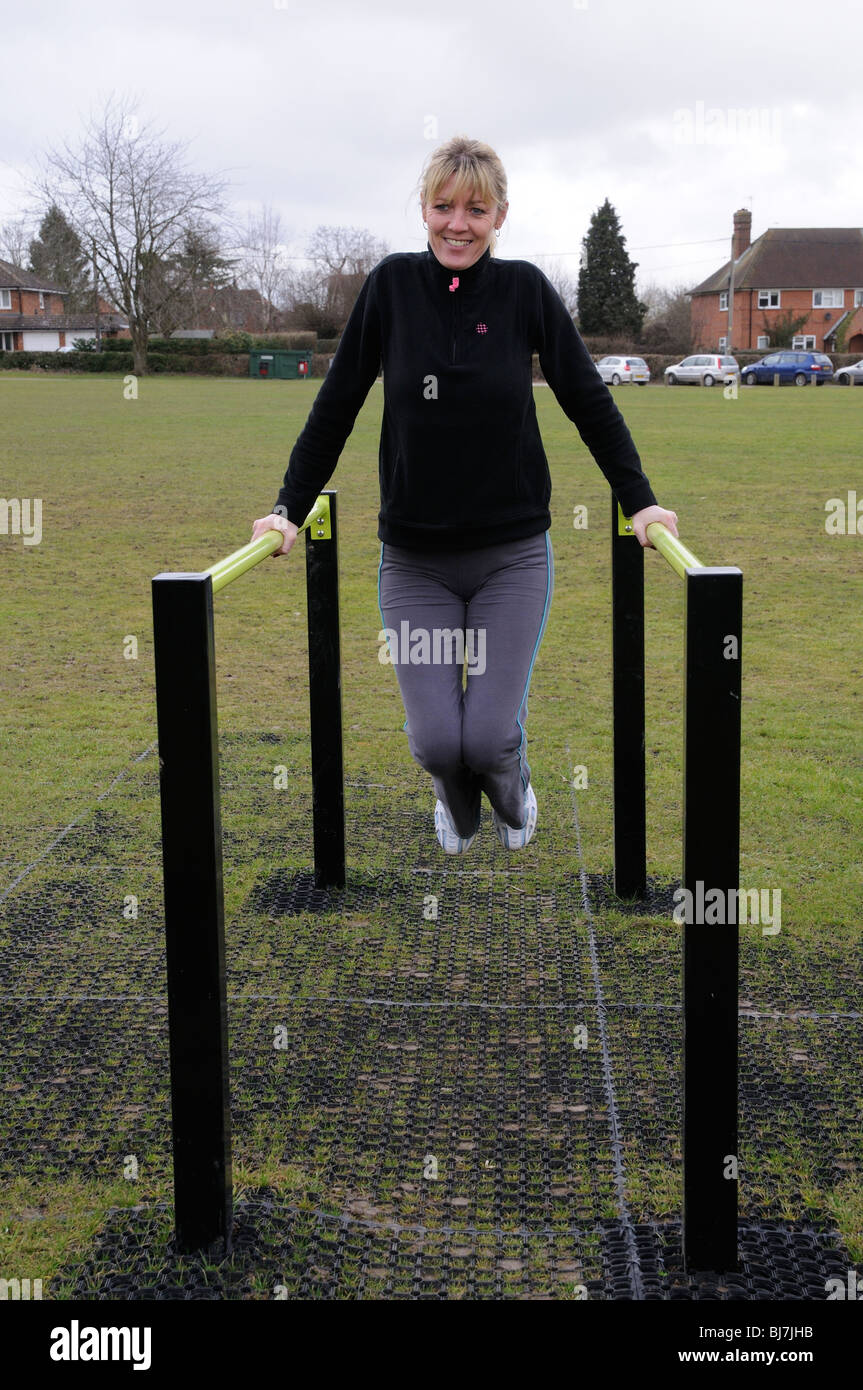 Woman using parallel bars outdoor gym equipment provided for public use ...