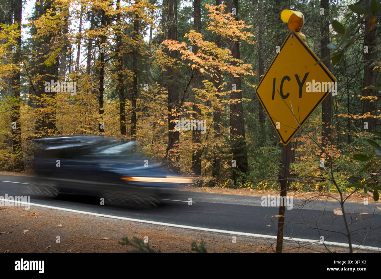 A car speeds by in a blur by a Icy road sign on a highway in Yosemite ...