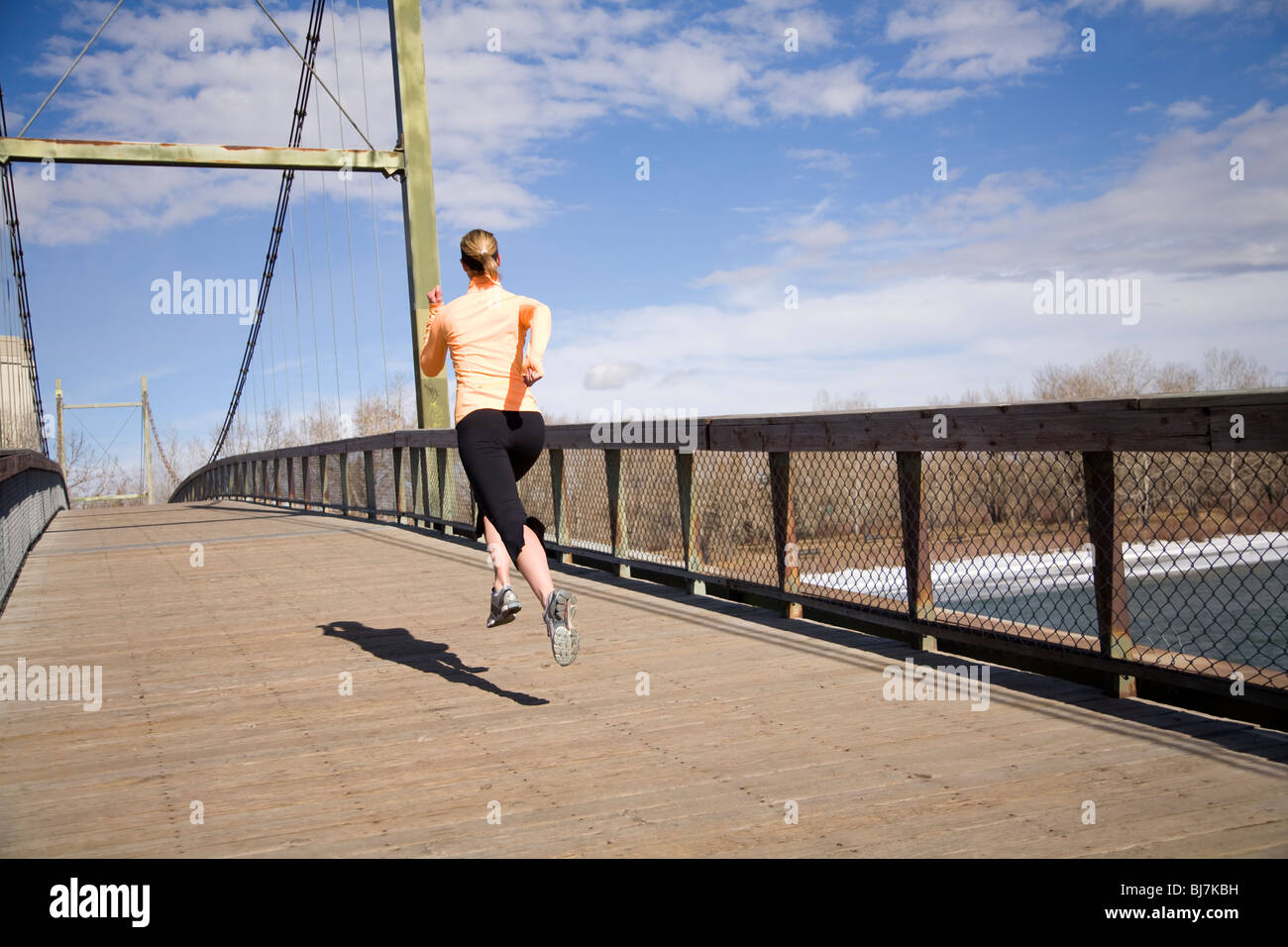 Woman running across a bridge away from camera Stock Photo - Alamy