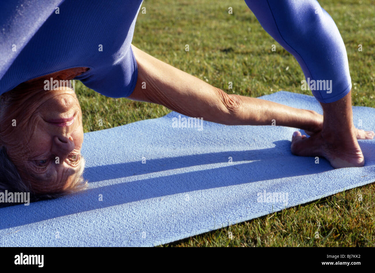 Mature female practising yoga outdoors. Yoga posture. Cropped landscape ...