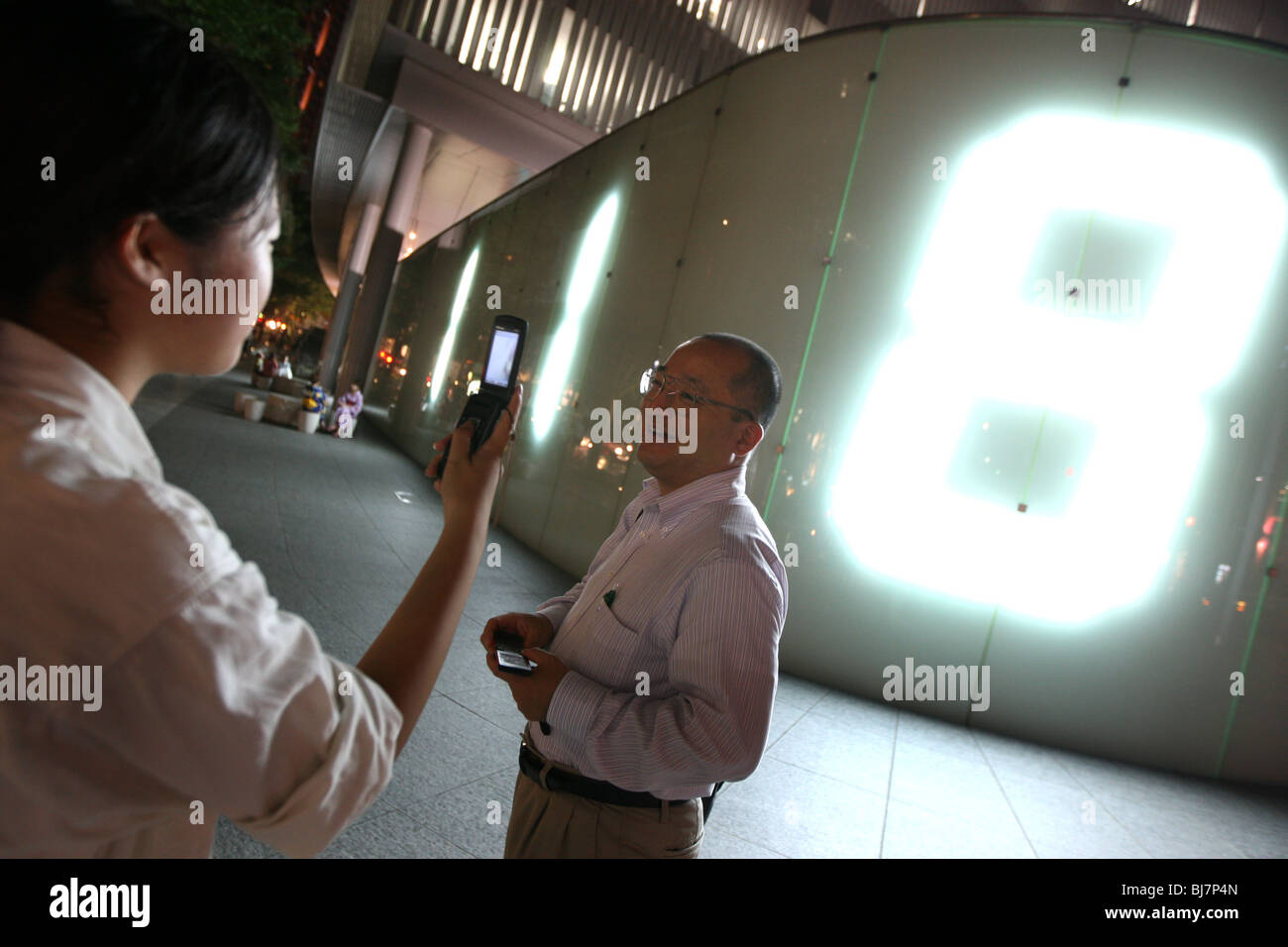Japanese people using mobile telephone in front of digital number ...