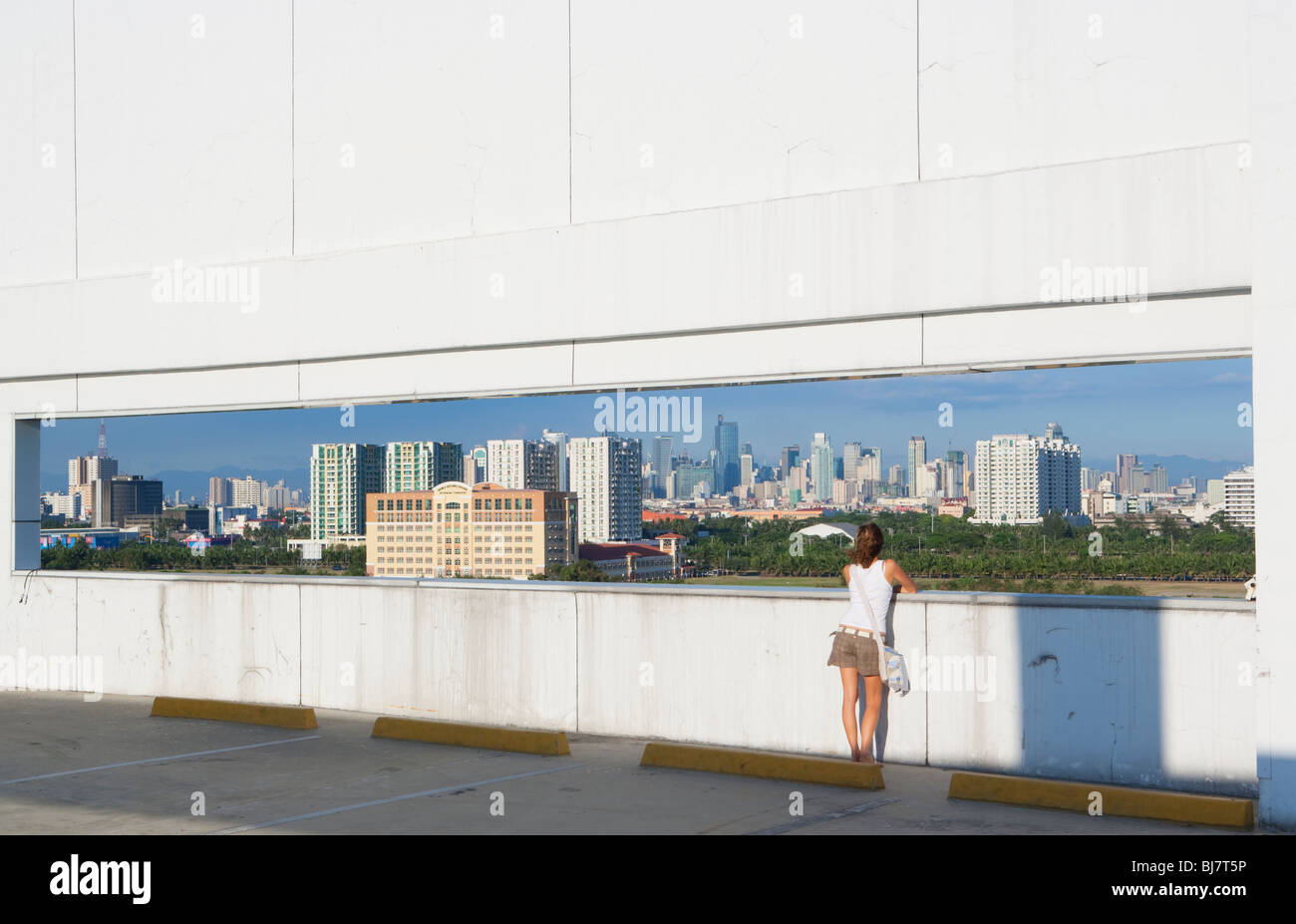 Girl looking at Manila skyline through panoramic window; Manila ...