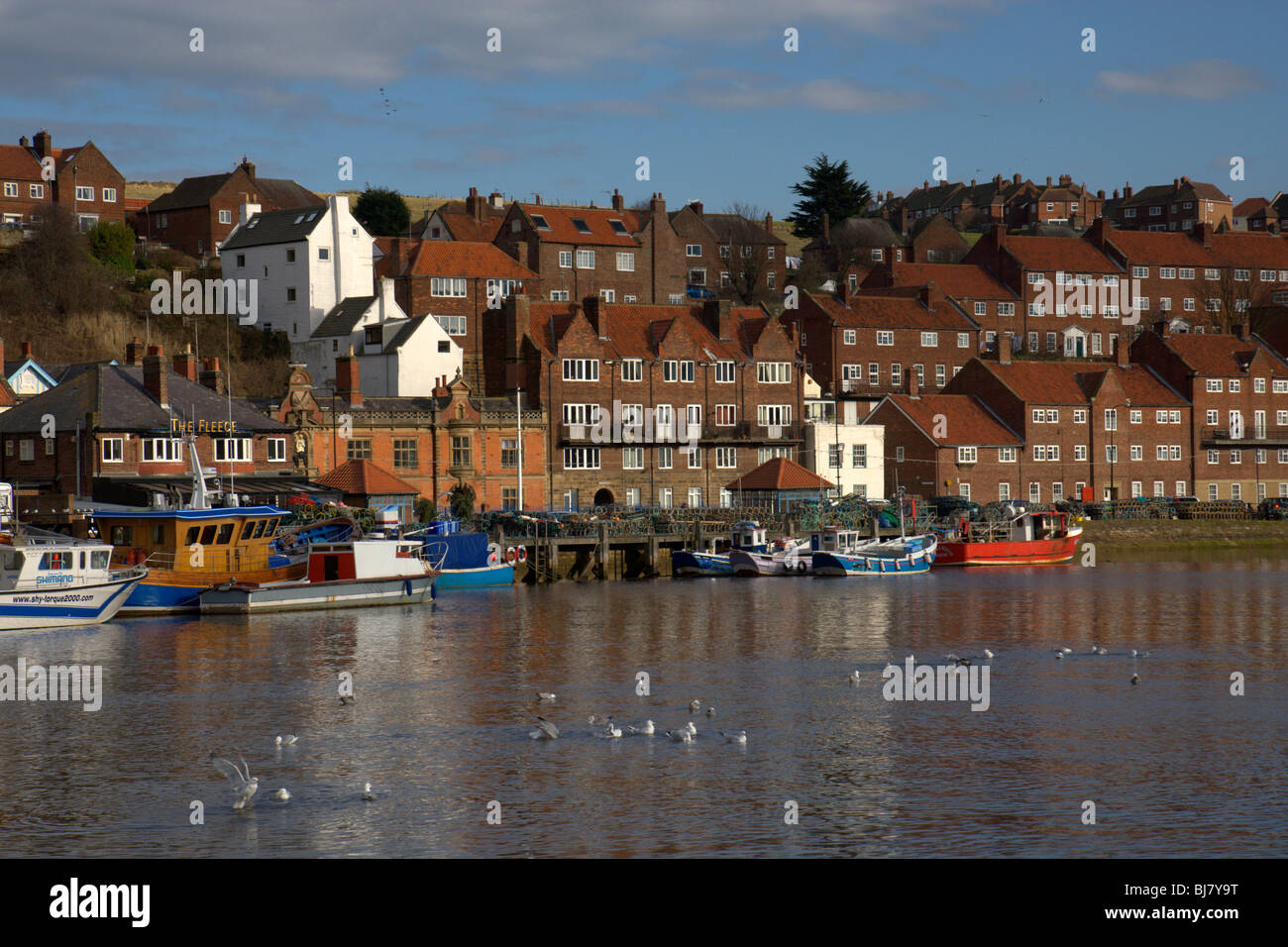 Picturesque area of Whitby by the harbourside. Gulls swim in the water ...