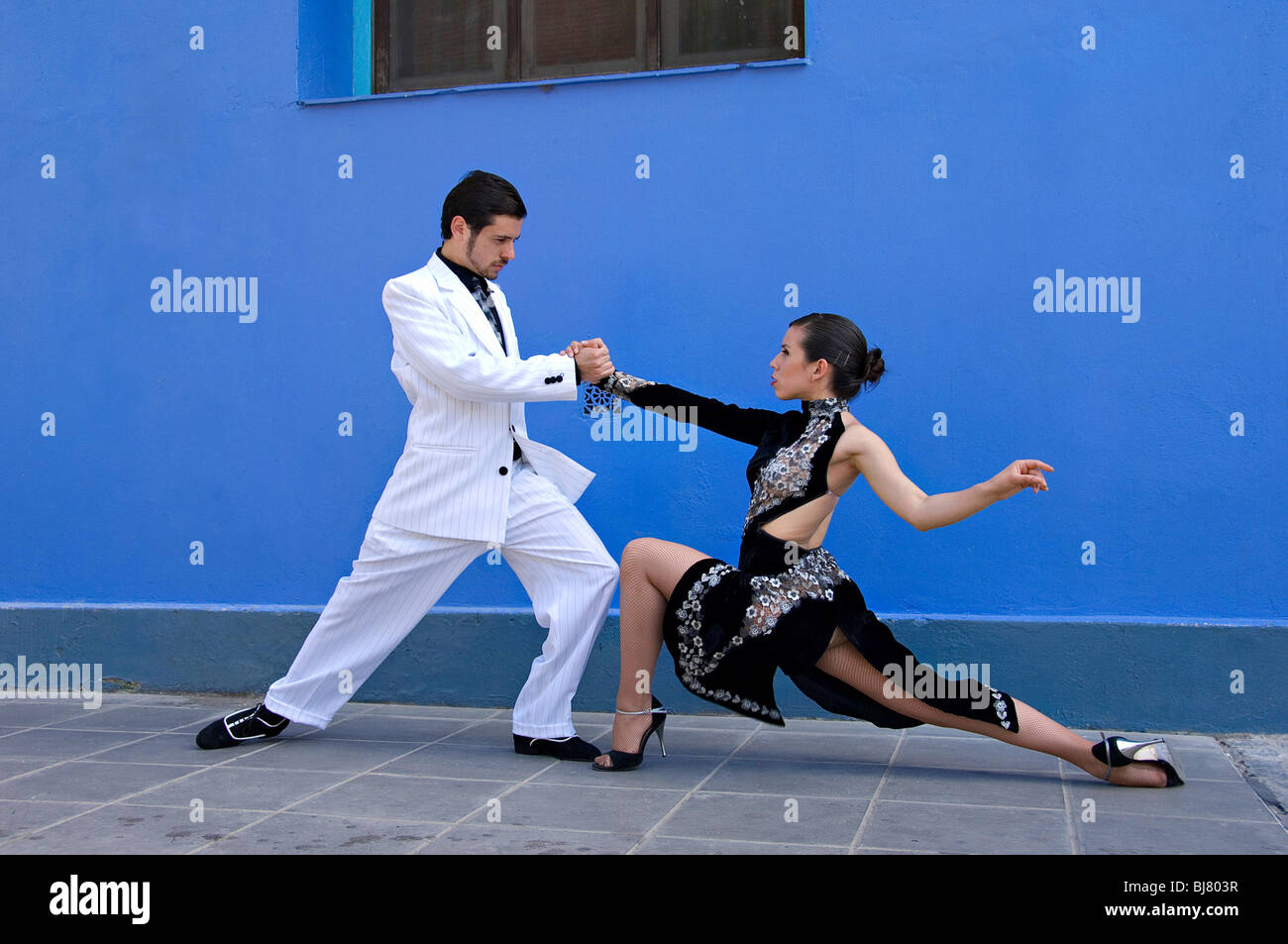 Two Professional Tango Dancers Dressed In Black And White Against A Plain Blue Wall In La Boca