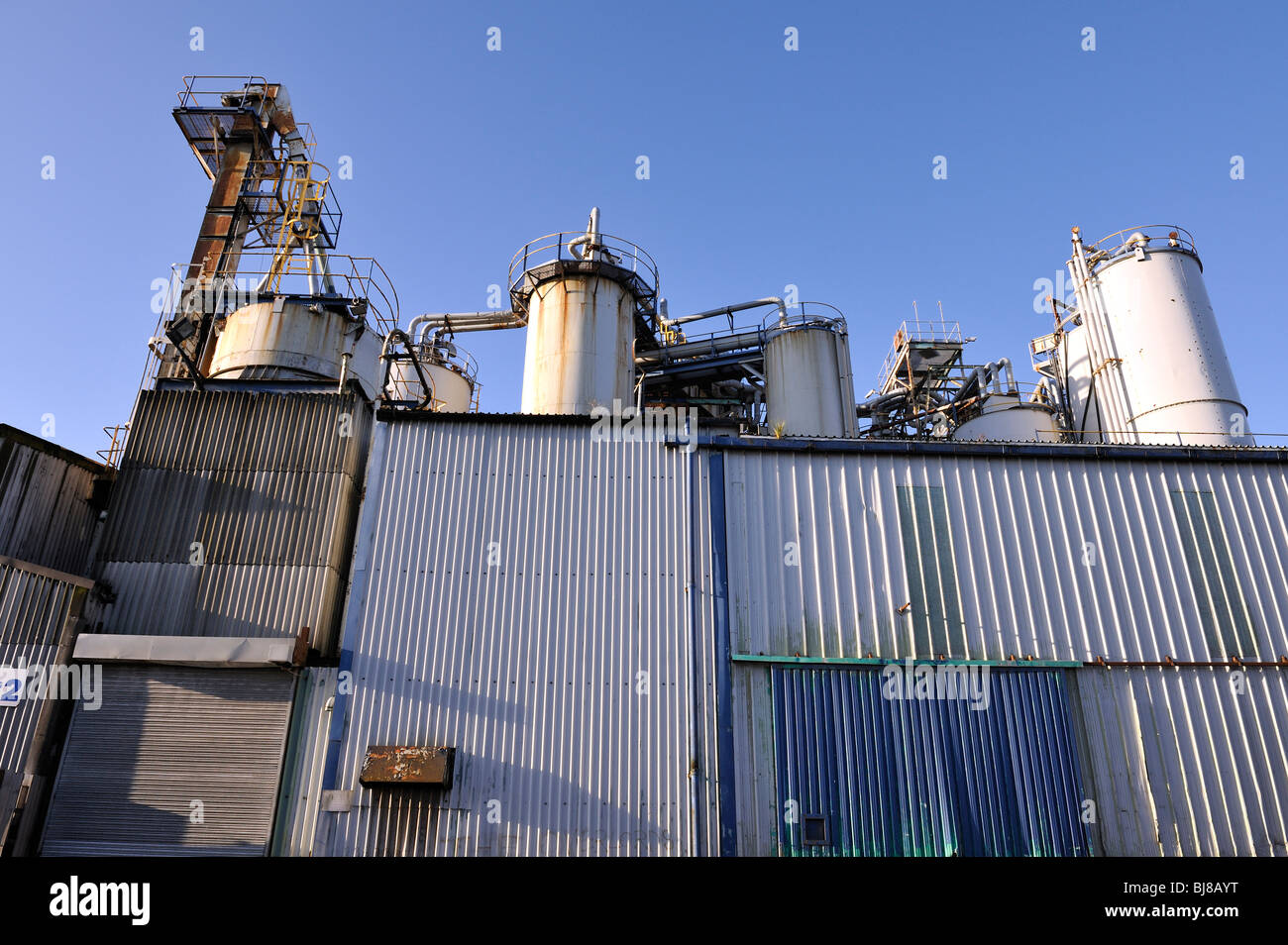 Rusting factory and steel storage tanks against bright blue sky Stock ...