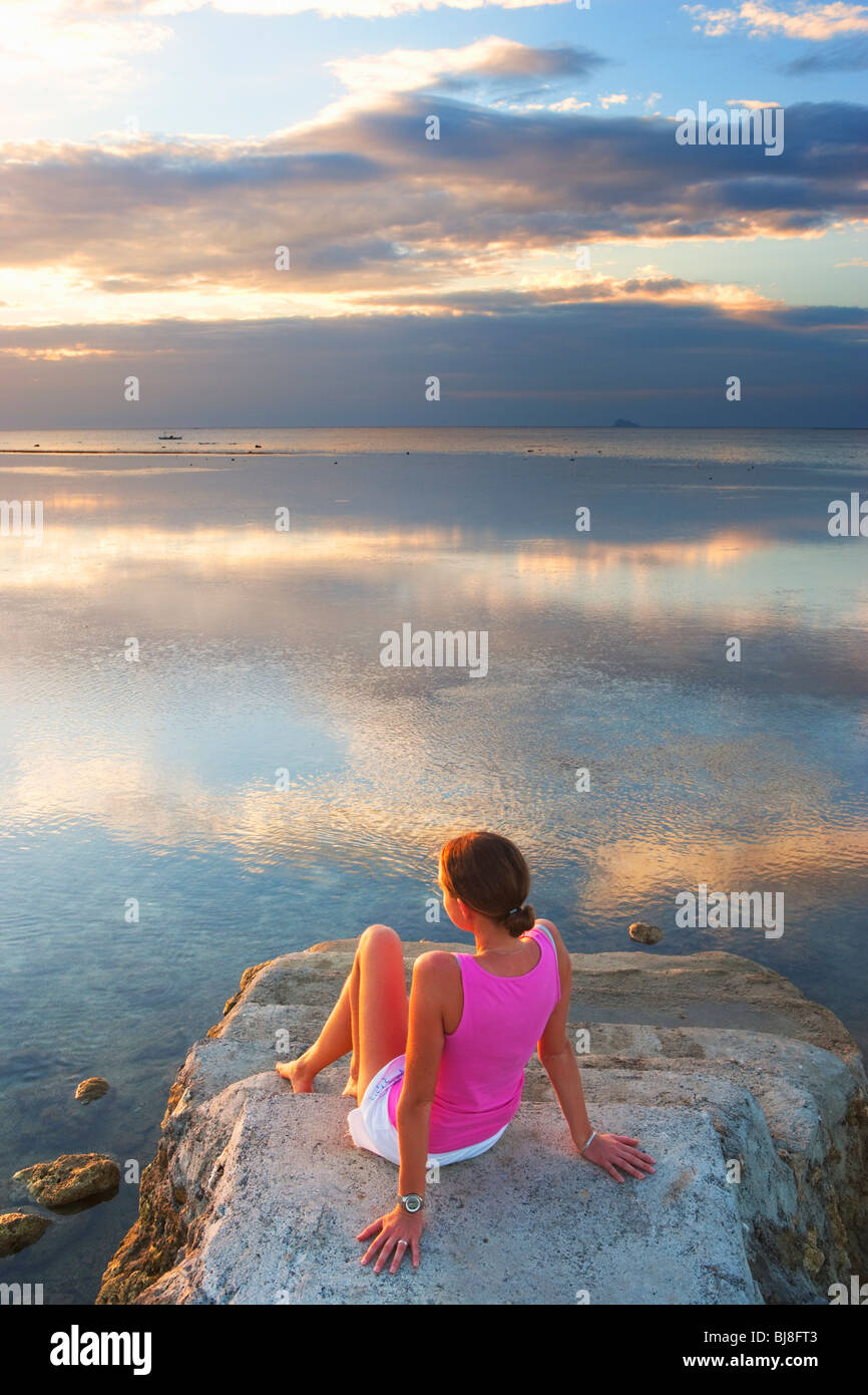 Girl sitting at end of pier looking into sunset Matabungkay; Batangas ...