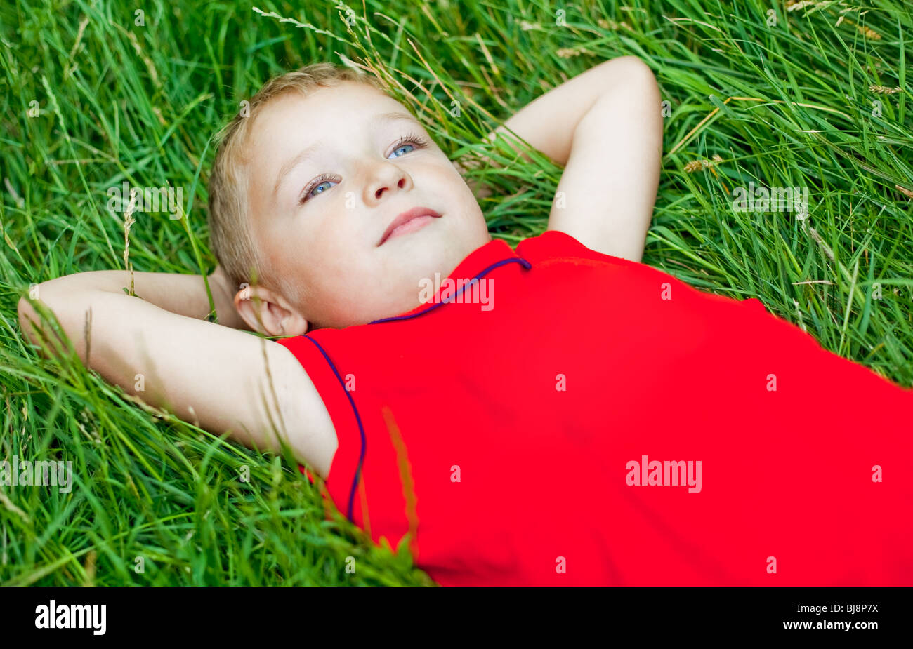 Pensive kid day dreaming in fresh grass Stock Photo - Alamy