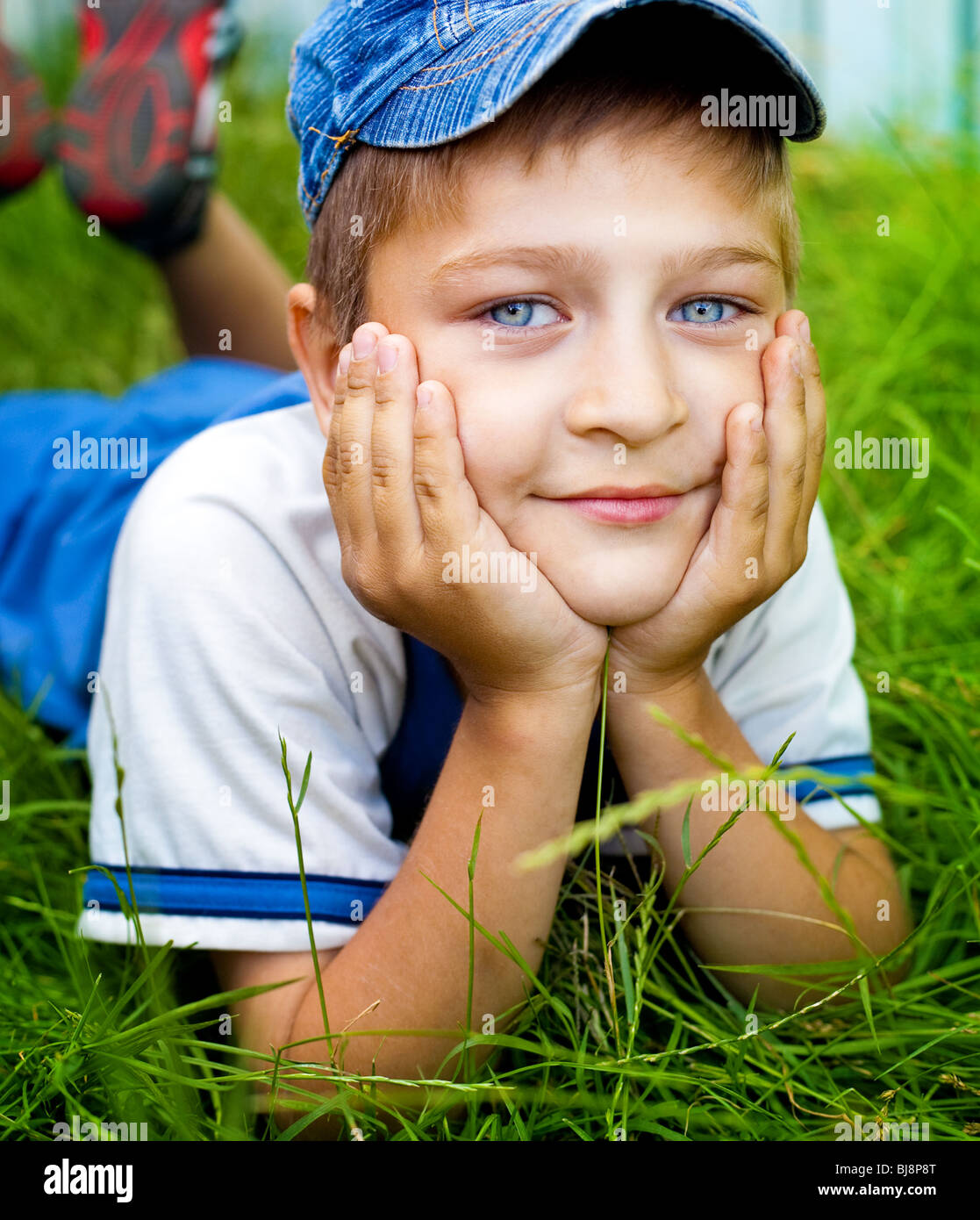 Cute happy kid laying on fresh grass outdoor Stock Photo - Alamy
