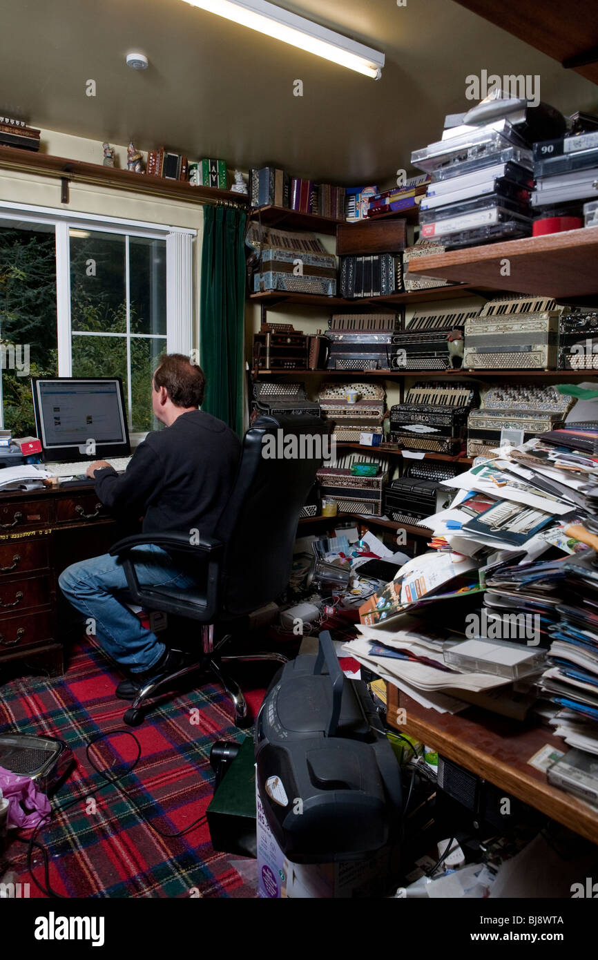 man in front of computer in a messy office filled with accordions and ...
