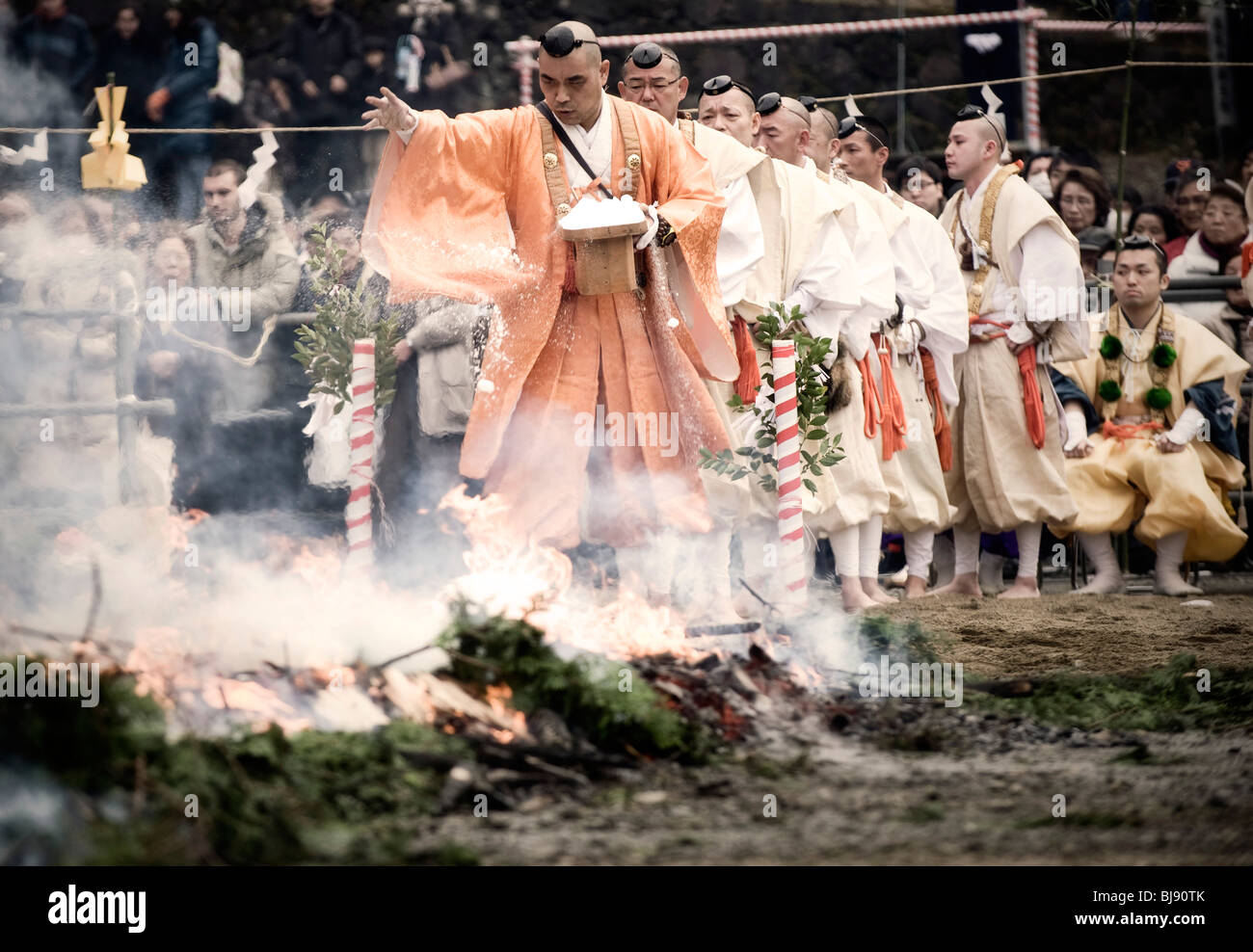 A Buddhist priest scatters salt over the flames as he walks across the ...
