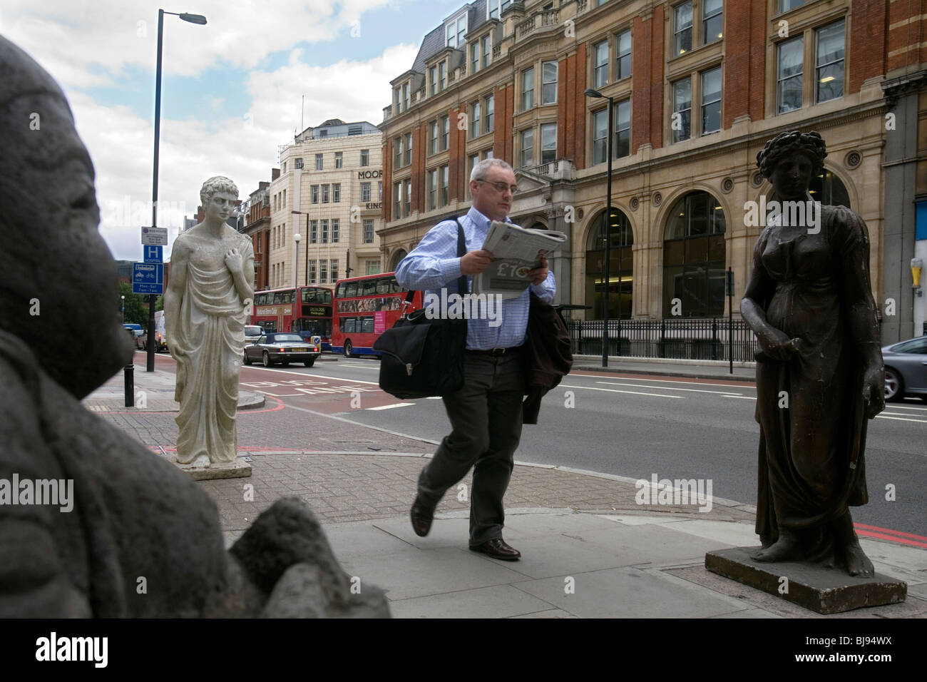 a man walking past some statues on a london pavement Stock Photo - Alamy