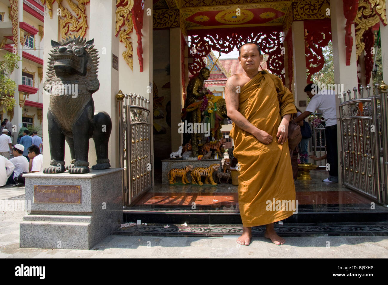 A monk poses in front of a shrine in the compound of Wat Bang Phra, a ...