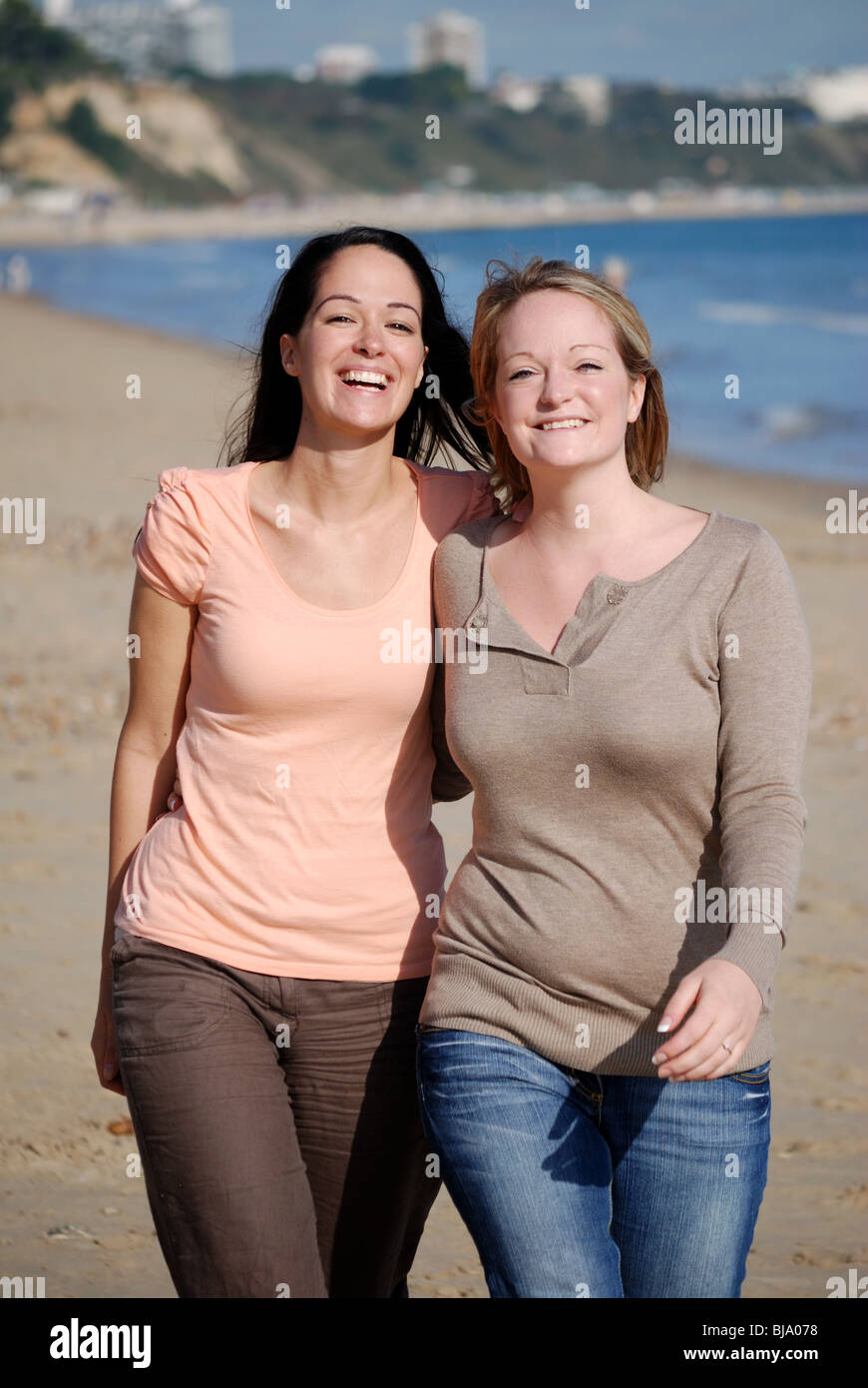 Two women laughing to camera at the beach Stock Photo - Alamy