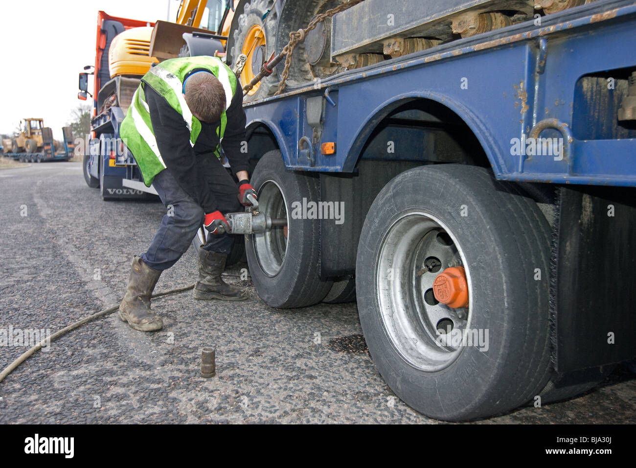 A Tyre Fitter working on a lorry wheel being changed at the roadside ...