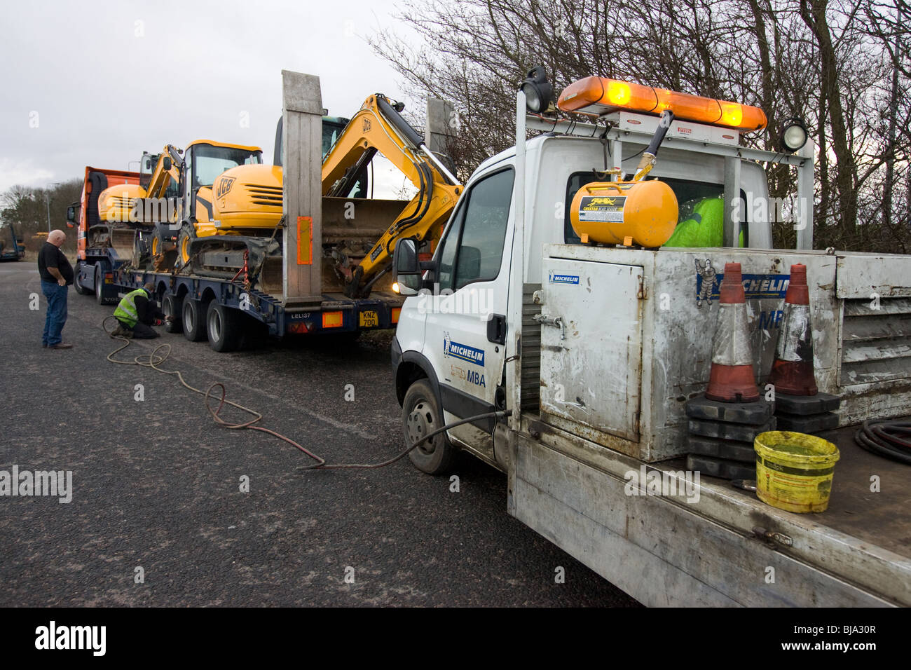 A Tyre Fitter working on a lorry wheel being changed at the roadside ...