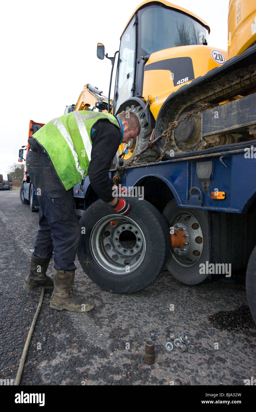 A Tyre Fitter working on a lorry wheel being changed at the roadside ...