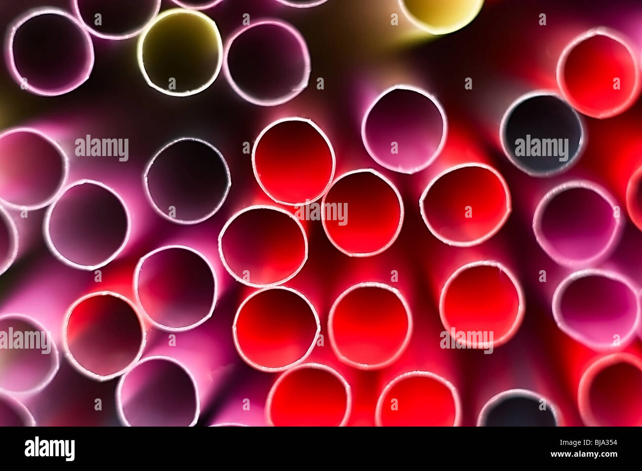 A closeup of drinking straws in the colors orange, red, rounds form ...
