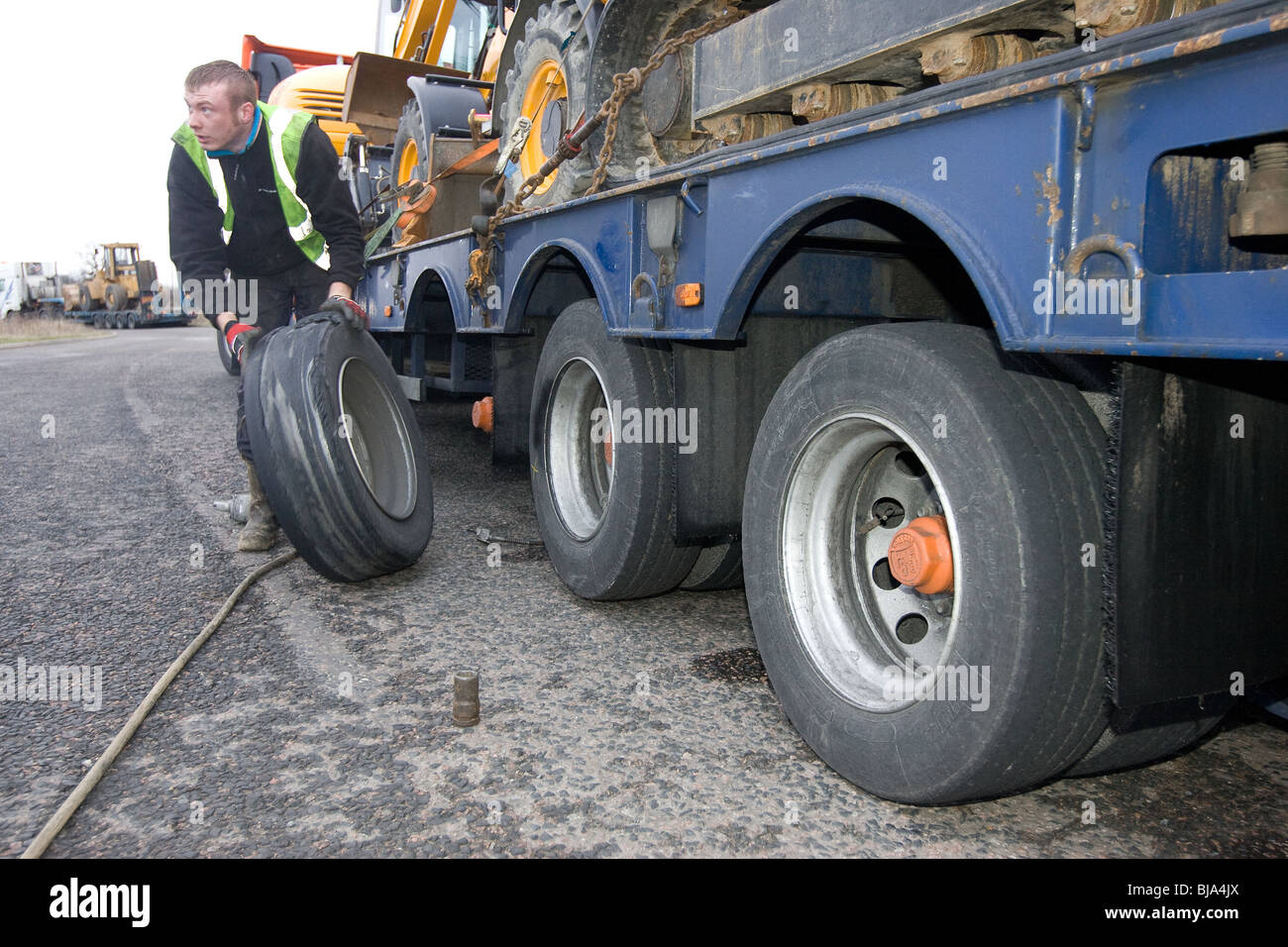 A Tyre Fitter working on a lorry wheel being changed at the roadside ...