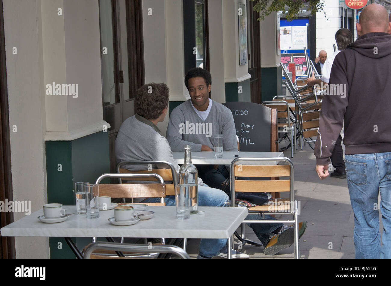 Two men chat outside a primrose hill cafe in London Stock Photo - Alamy