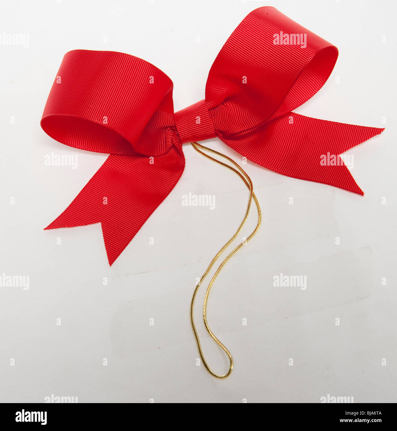 Large red bow on white background with gold thread hanging down Stock ...