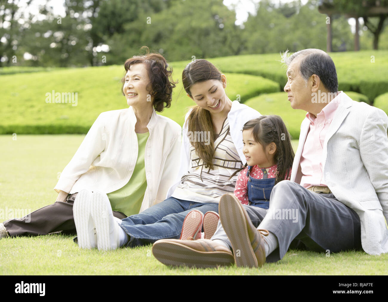 Three-generation family sitting on grass Stock Photo - Alamy