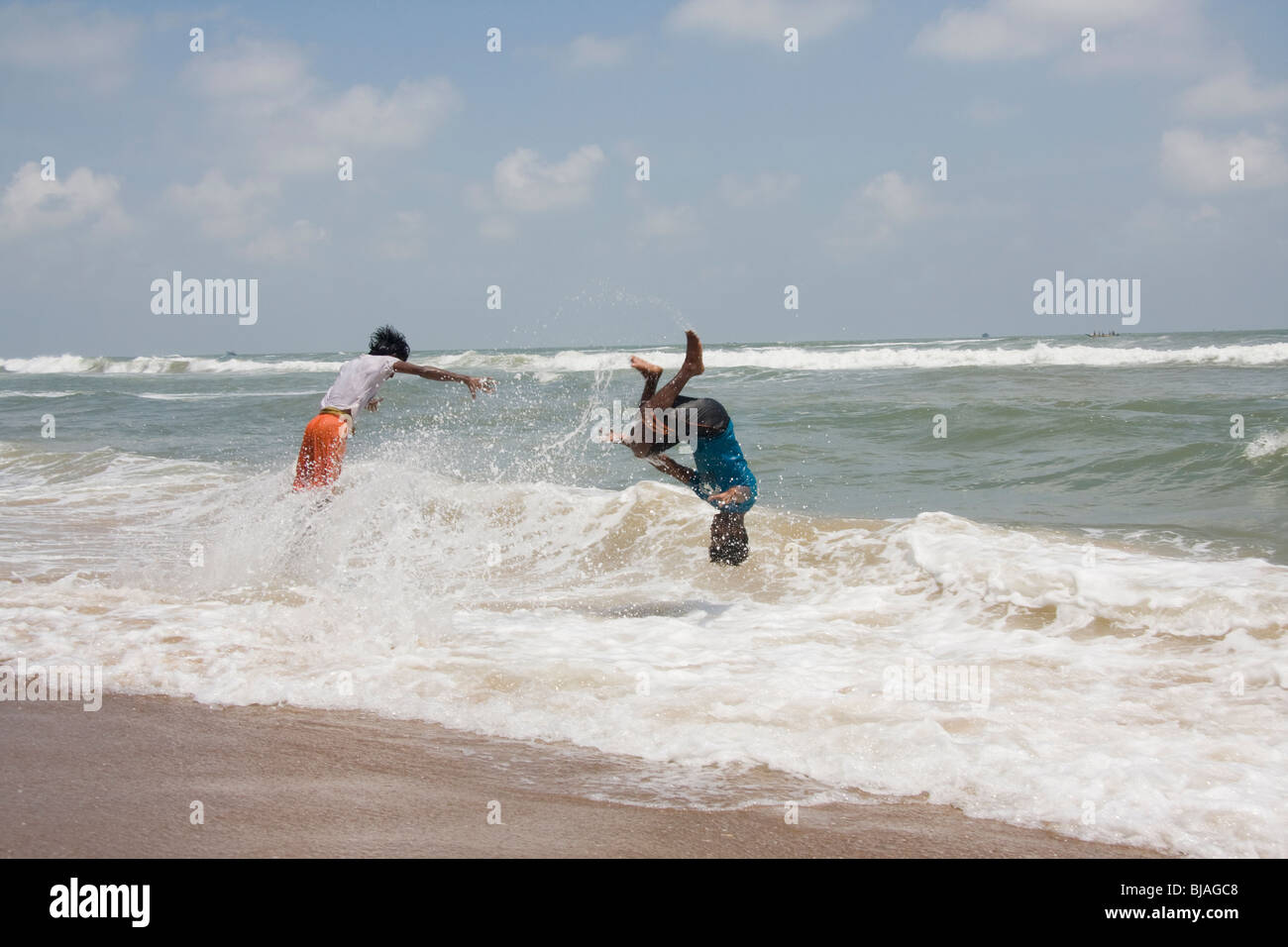 Two young men do somersault sin the surf at Puri beach, Orissa, India ...
