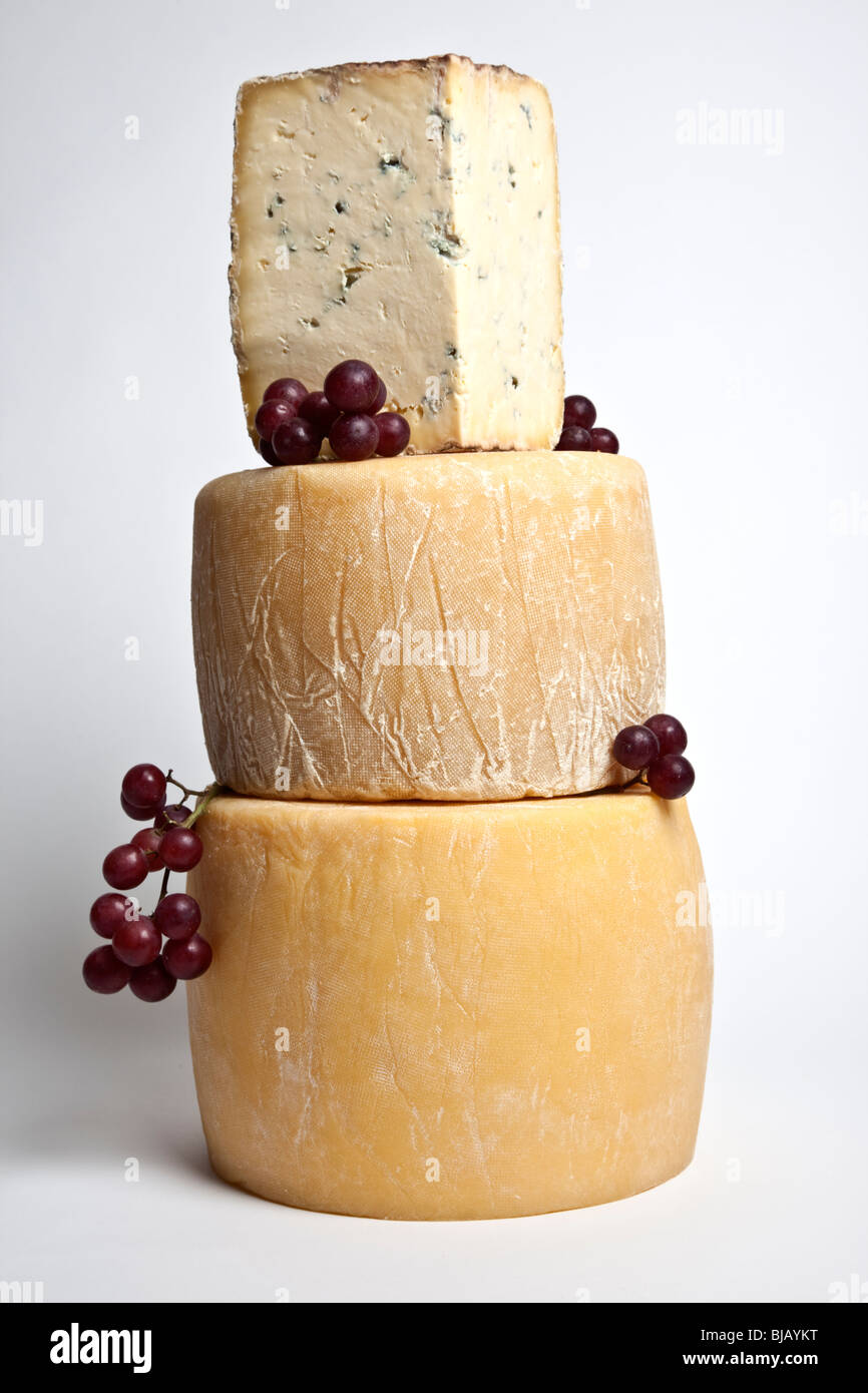 Two whole round cheeses with a large wedge of blue cheese in a tower ...