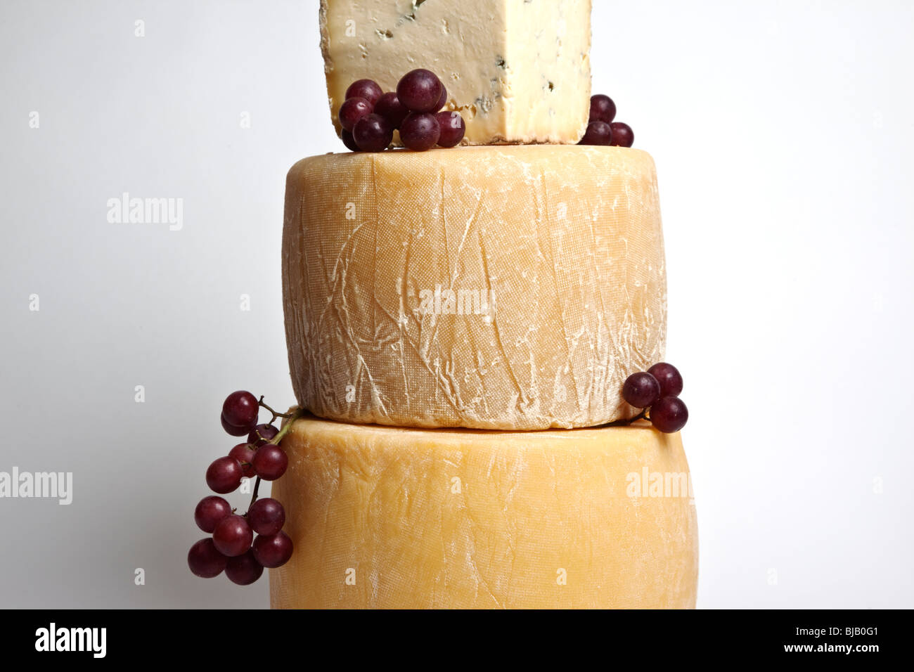 Two whole round cheeses with a large wedge of blue cheese in a tower ...