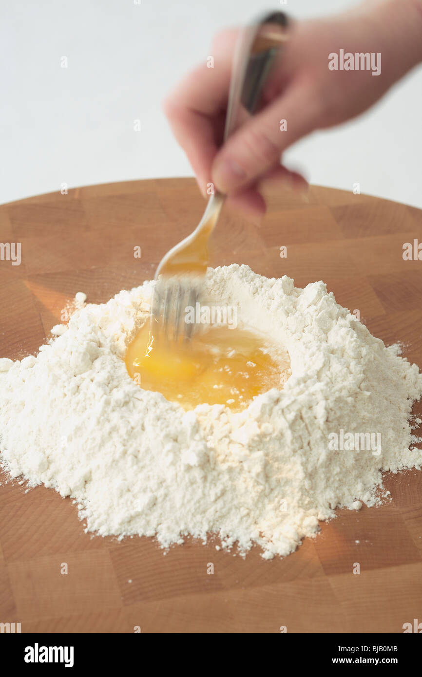Hand mixing fresh pasta ingredients with a fork Stock Photo - Alamy