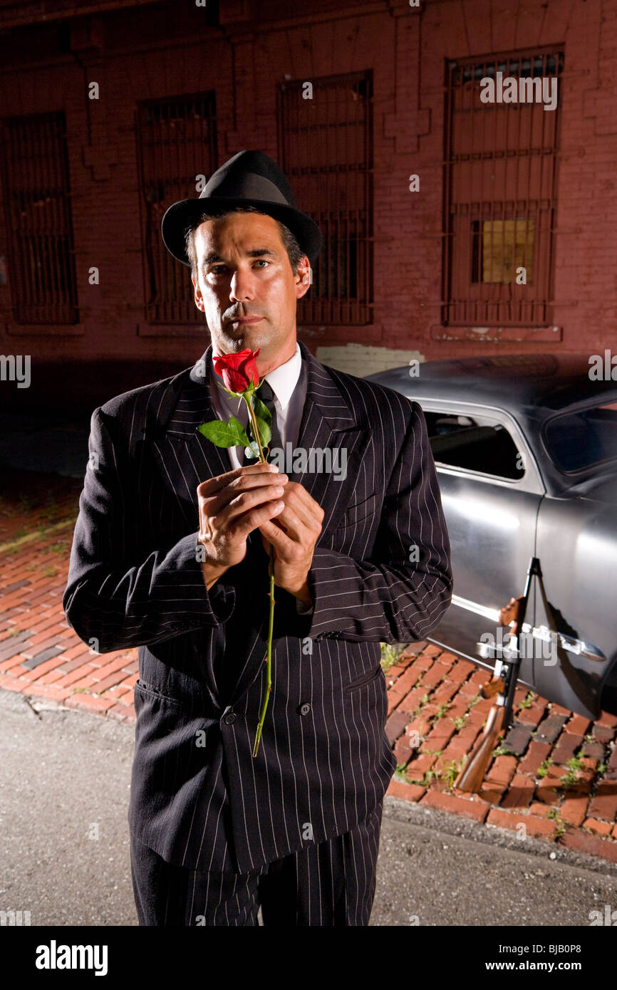 Gangster holding rose, Tommy gun leaning against car in background ...