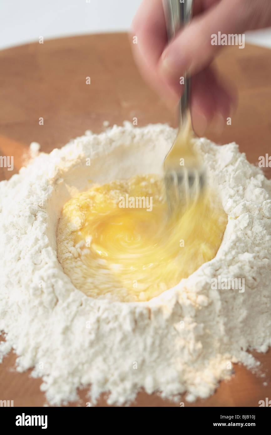 Hand mixing fresh pasta ingredients with a fork Stock Photo - Alamy