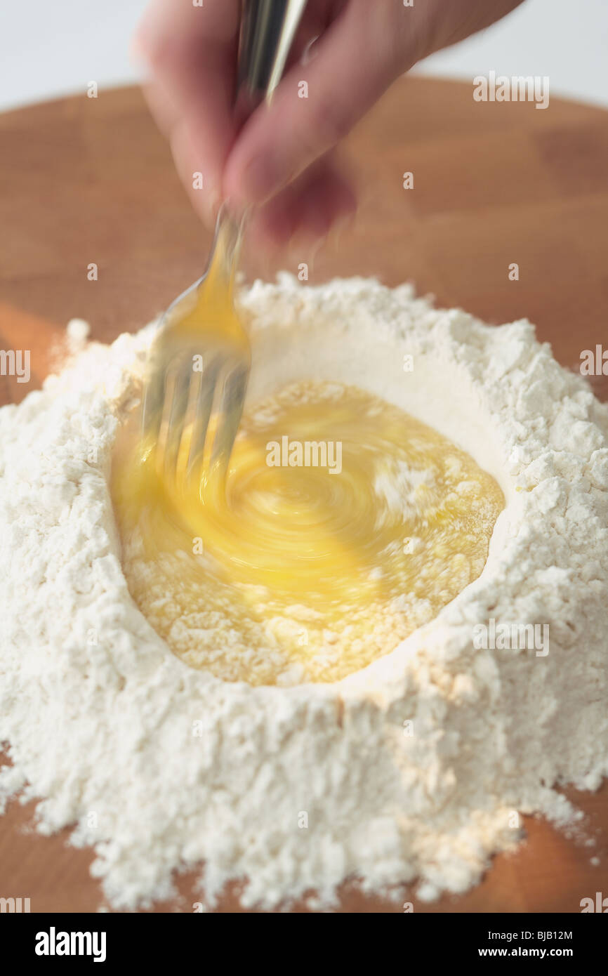 Hand mixing fresh pasta ingredients with a fork Stock Photo - Alamy