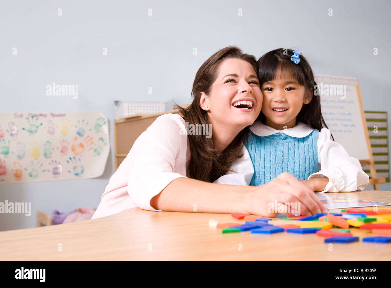 Smiling teacher helping cute little Asian child in preschool Stock ...