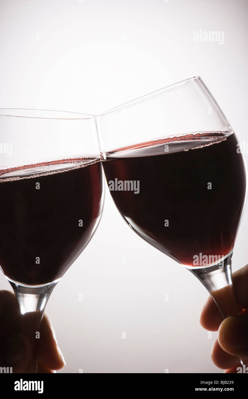 Man and woman toasting with red wine, close-up of hands, side view ...