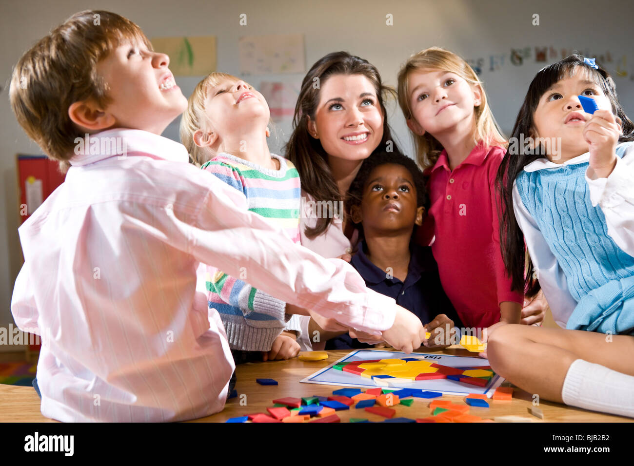 Teacher with preschool children smiling in classroom looking up Stock ...
