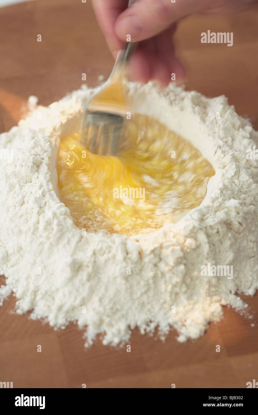 Hand mixing fresh pasta ingredients with a fork Stock Photo - Alamy