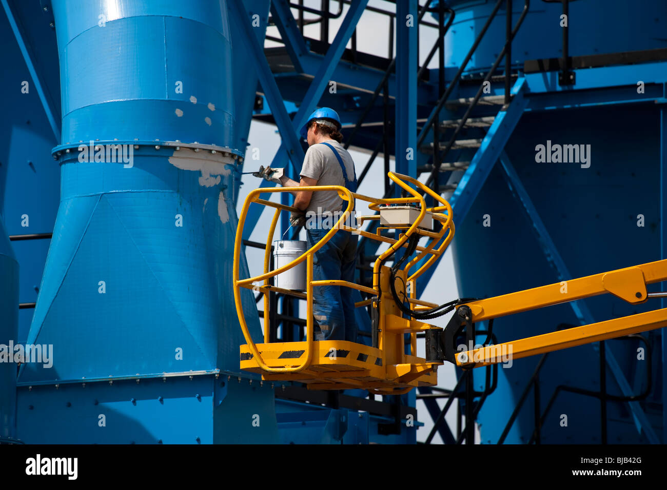 Construction worker in cherry picker working on industrial plant Stock ...