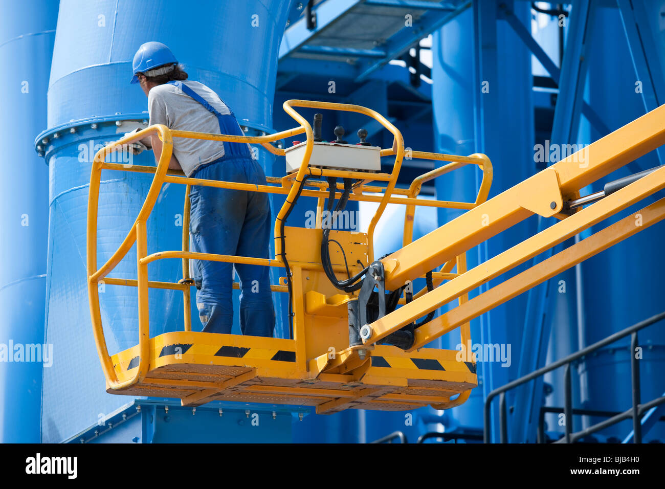 Construction worker in cherry picker working on industrial plant Stock ...