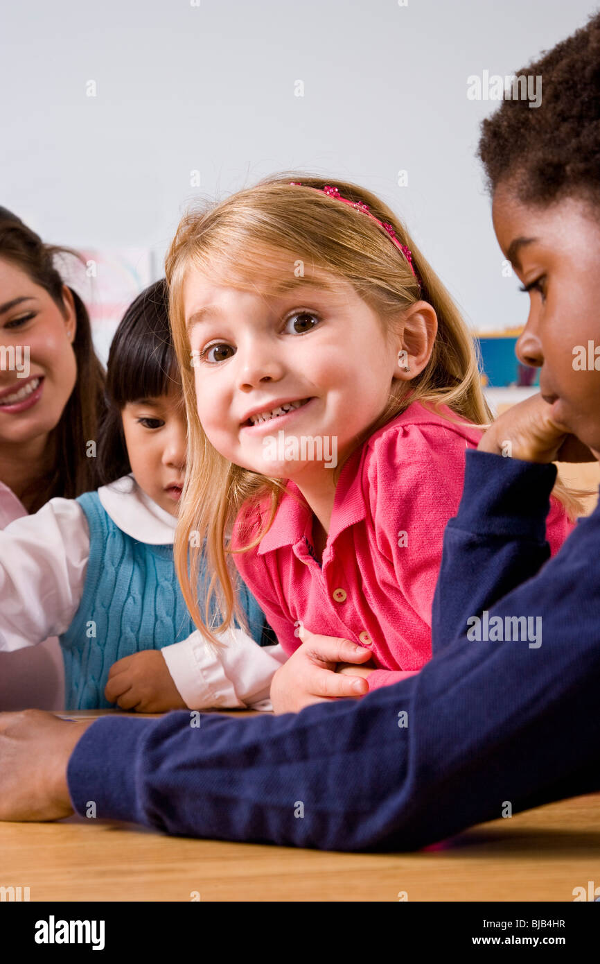 Eager little girl smiling with friends in preschool Stock Photo - Alamy