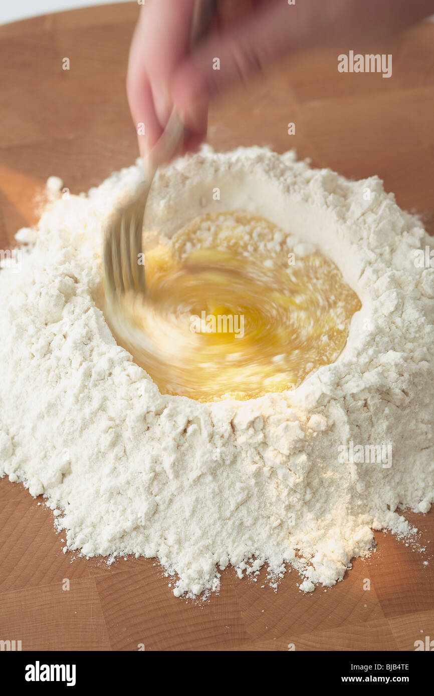 Hand mixing fresh pasta ingredients with a fork Stock Photo - Alamy
