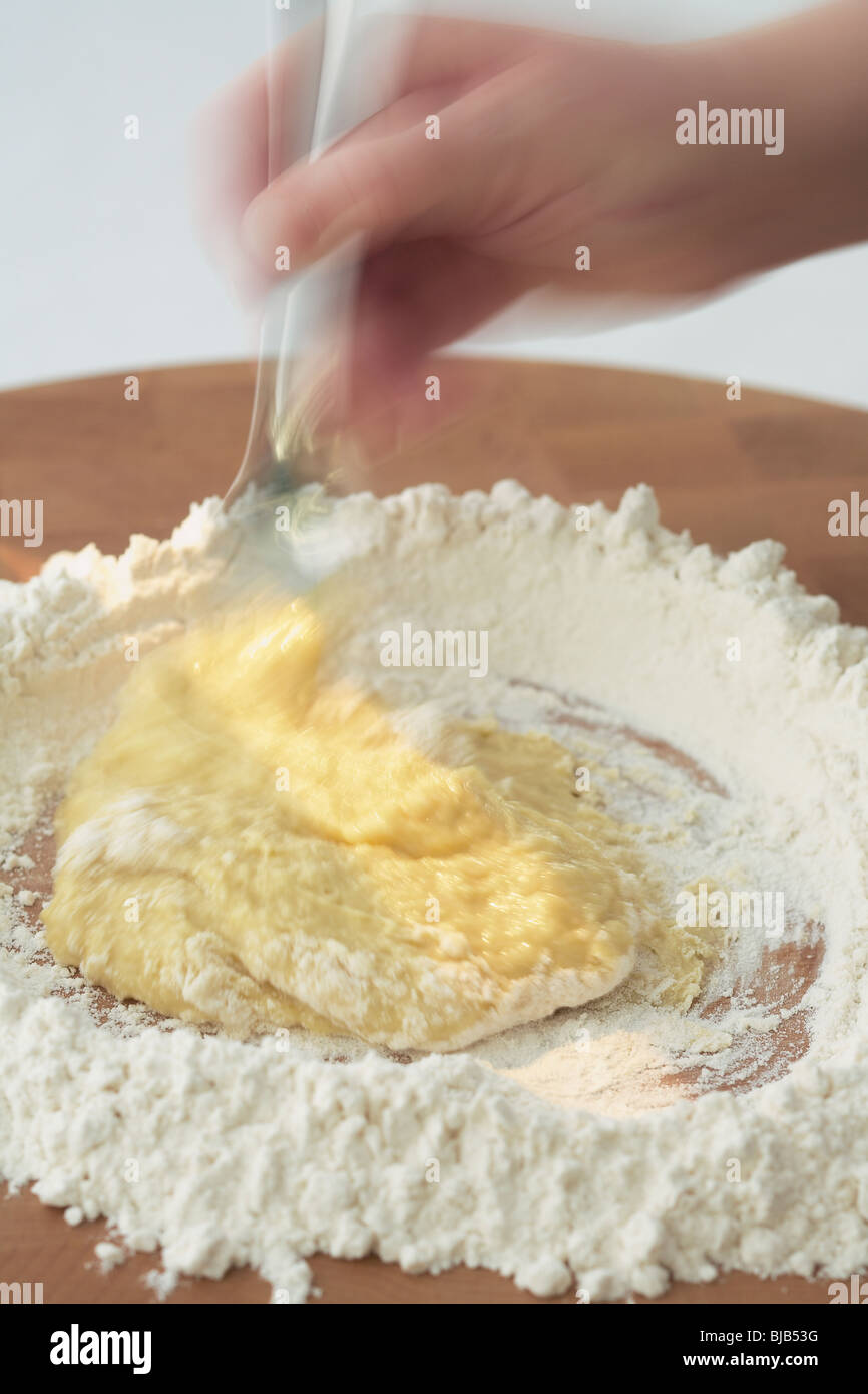 Hand mixing fresh pasta ingredients with a fork Stock Photo - Alamy