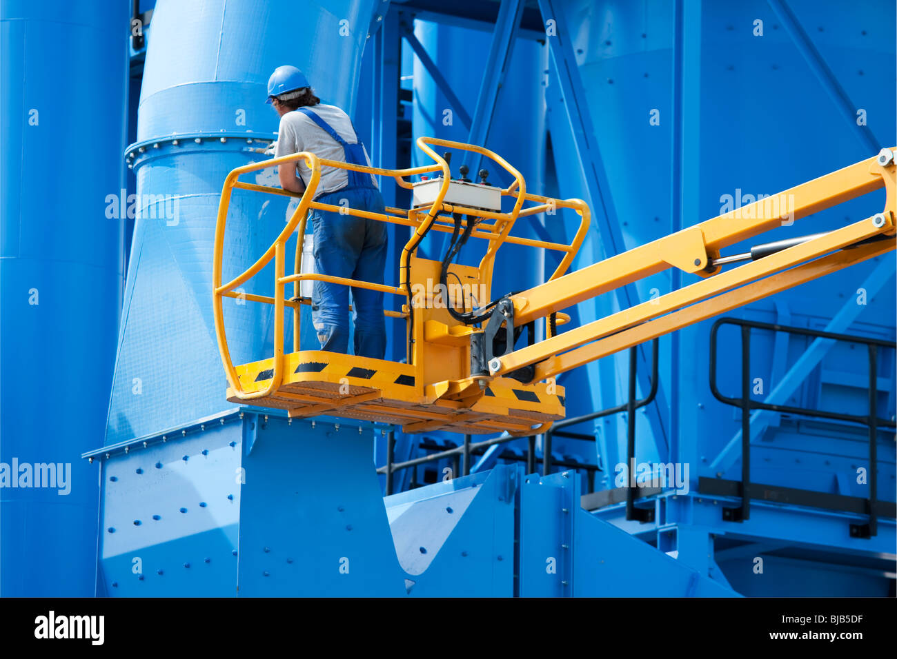 Construction worker in cherry picker working on industrial plant Stock ...
