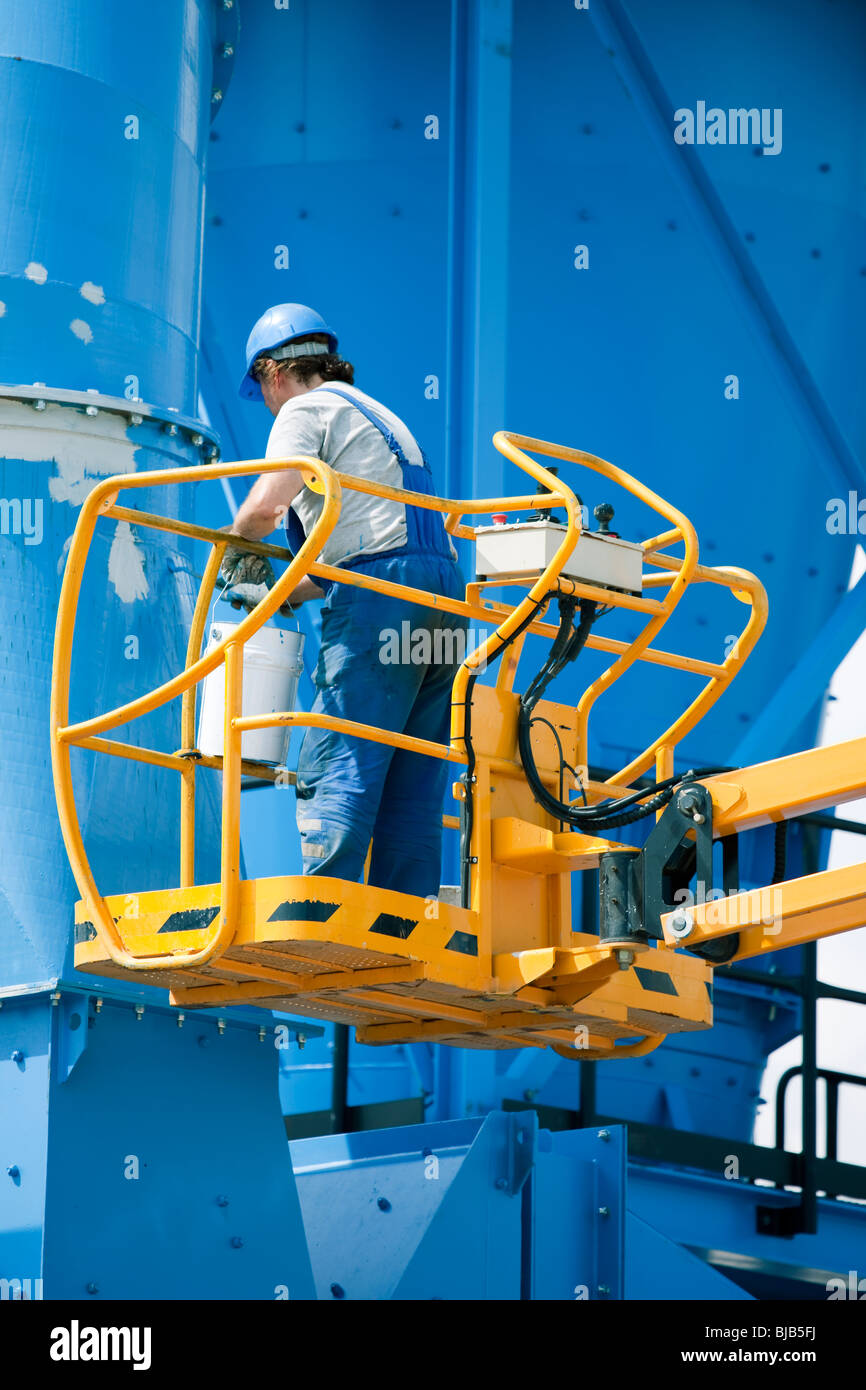 Painter painting industrial pipe from a cherry picker Stock Photo - Alamy